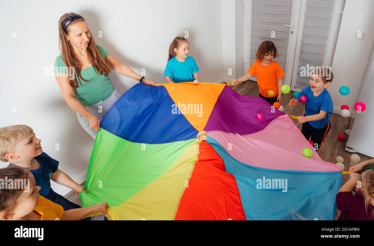 Teacher and kindergarten kids playing with colorful parachute Stock ...