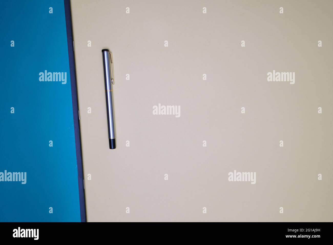 Office flat lay with pen and notebook placed on a light orange ...