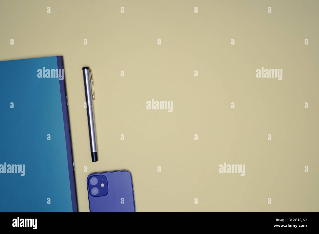 Office flat lay with pen, mobile and notebook placed on a light orange ...