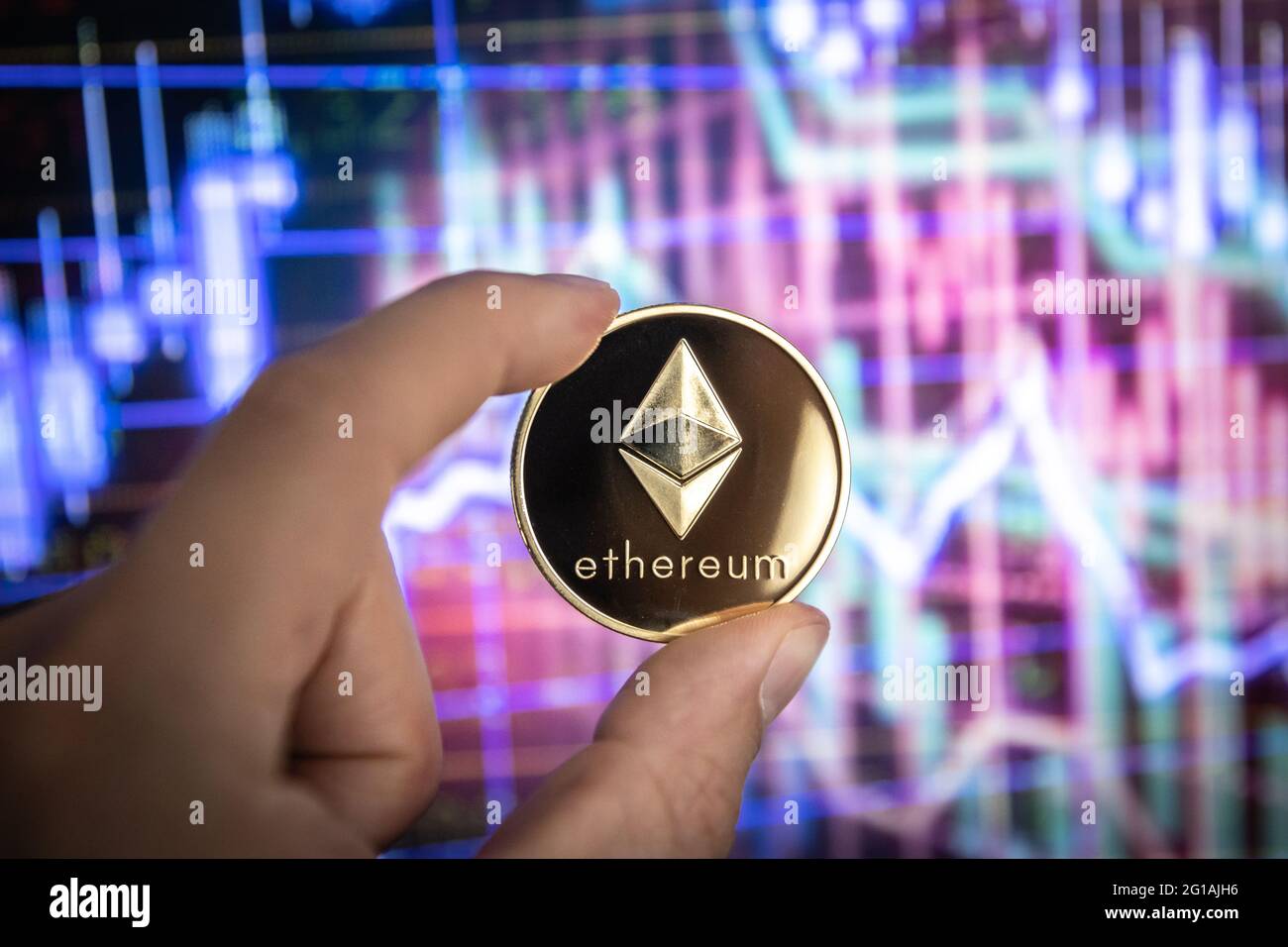 Ethereum cryptocurrency, physical coin in front of colorful charts and ...