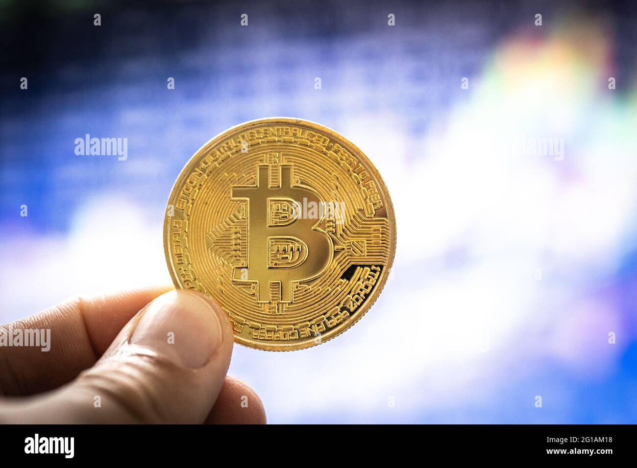 Bitcoin physical coin held between fingers Stock Photo - Alamy