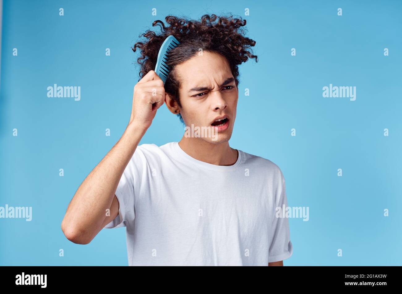 indignant guy combing hair with blue comb on isolated background ...