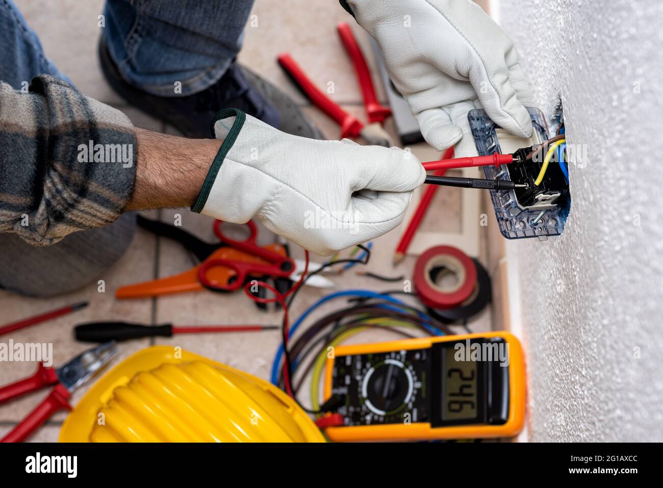 View from above. Electrician worker at work with the tester measures ...