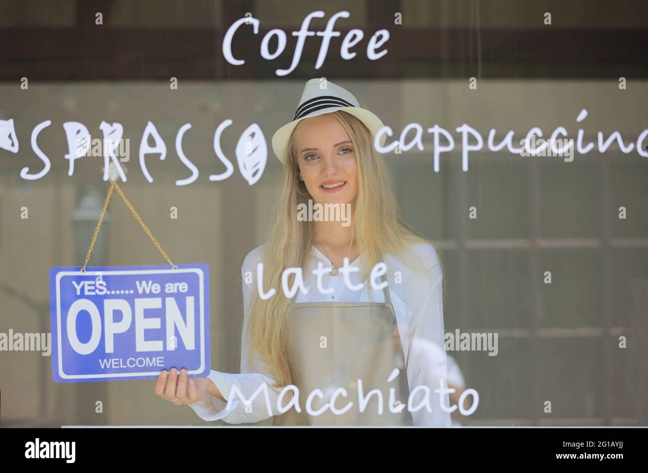 Beautiful blonde hair girl standing by open shop sign plate at door ...