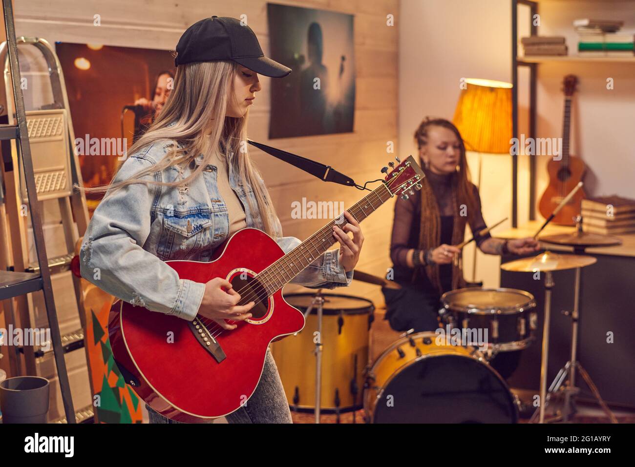 Female musicians playing guitar and drum in modern studio Stock Photo ...