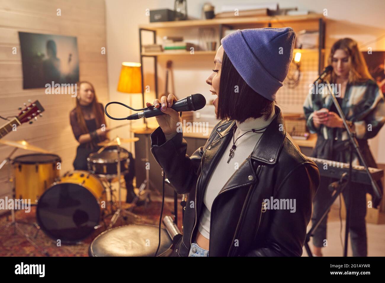 Stylish female singing in microphone while ecording song in studio ...