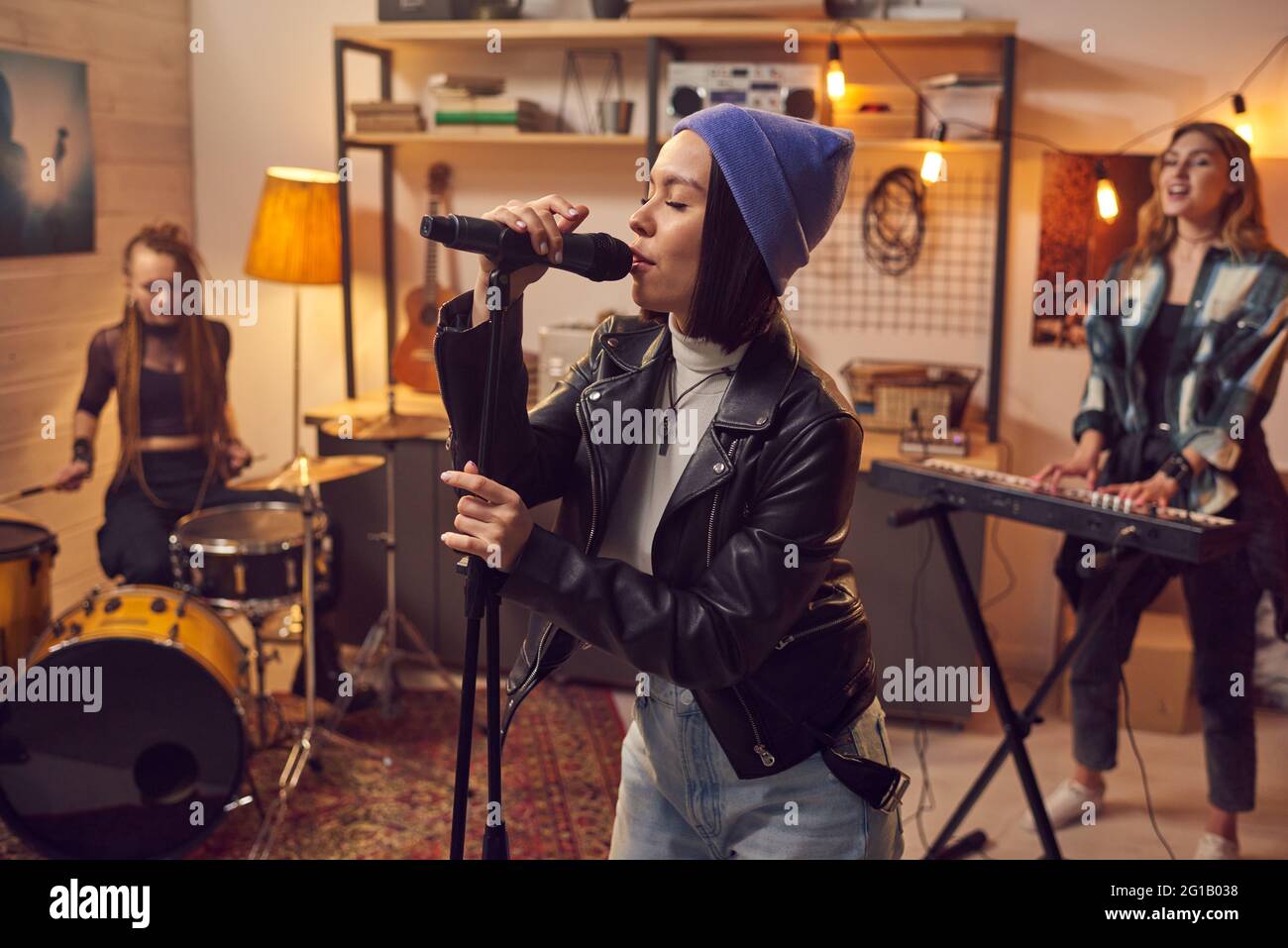 Young female singer and her band recording new songs in their studio ...