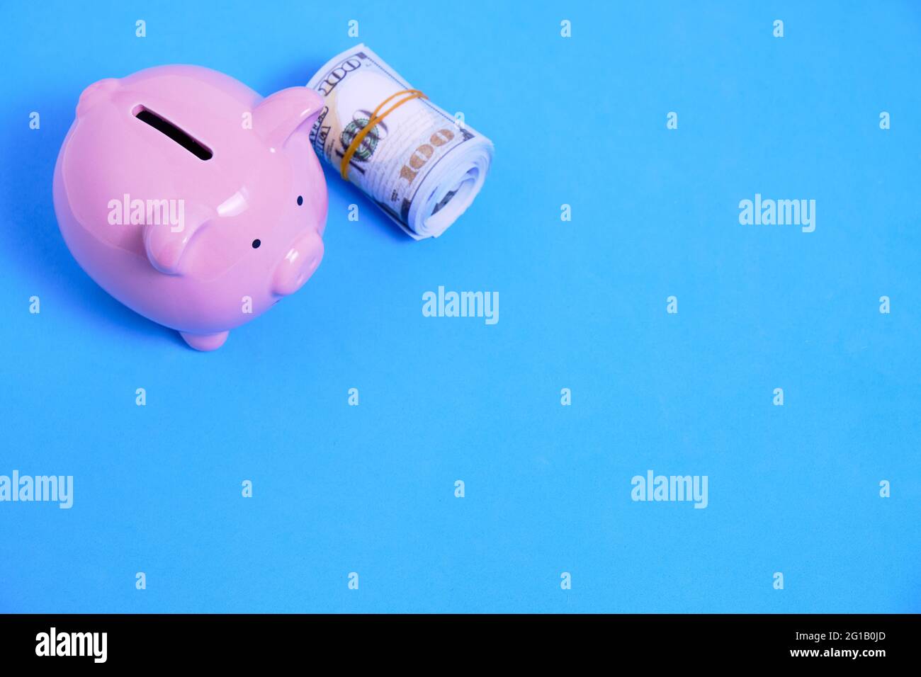 Pink Piggy Bank and a Stack of Hundred Dollar Bills on a Blue ...