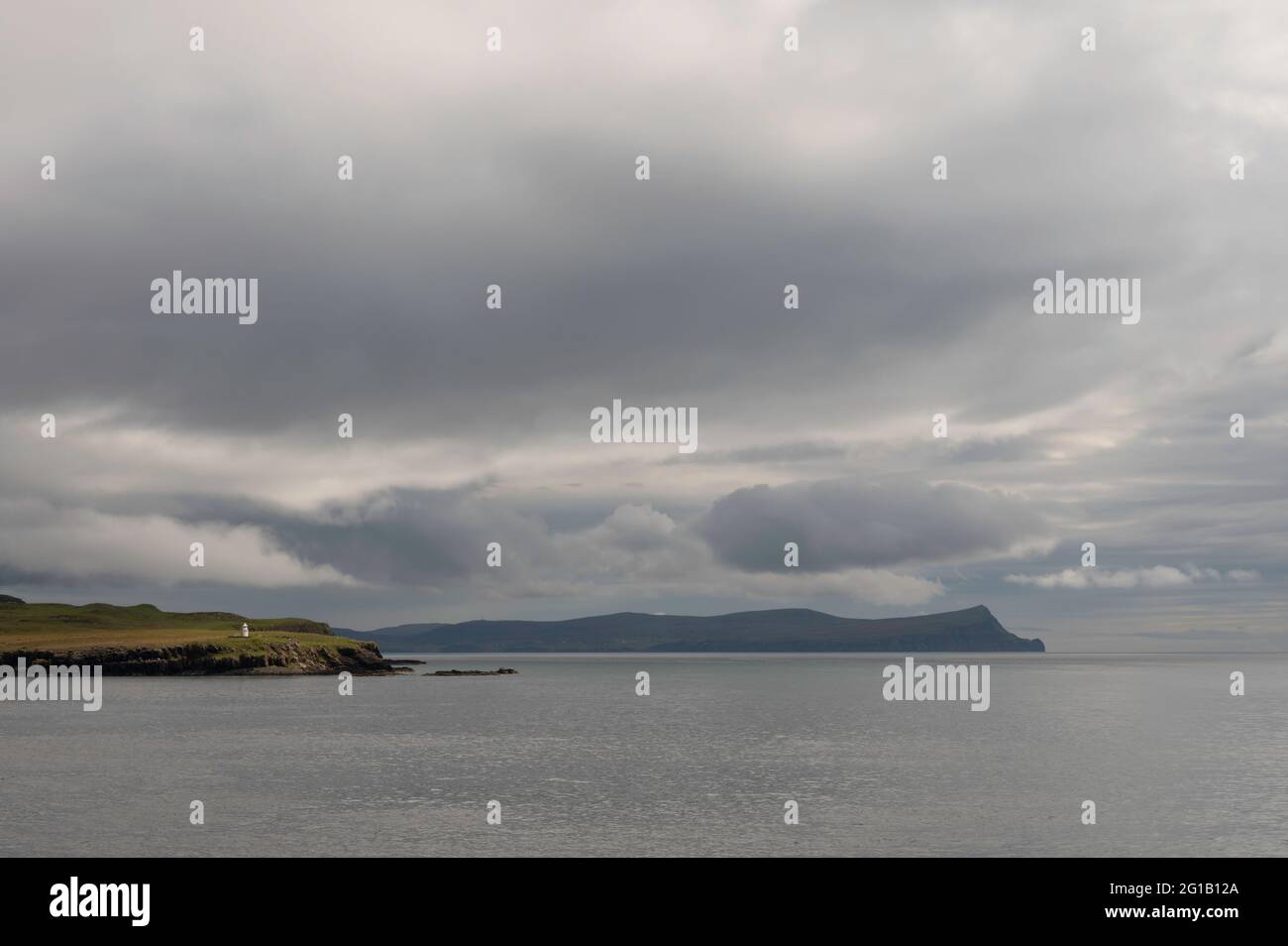 View of Isle of Skye from ferry. Vaternish Lighthouse in sunlight, dark ...