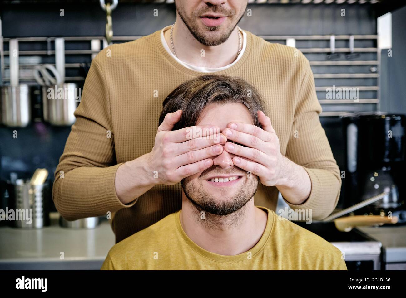 Young man keeping hands on eyes of his boyfriend in the kitchen Stock ...