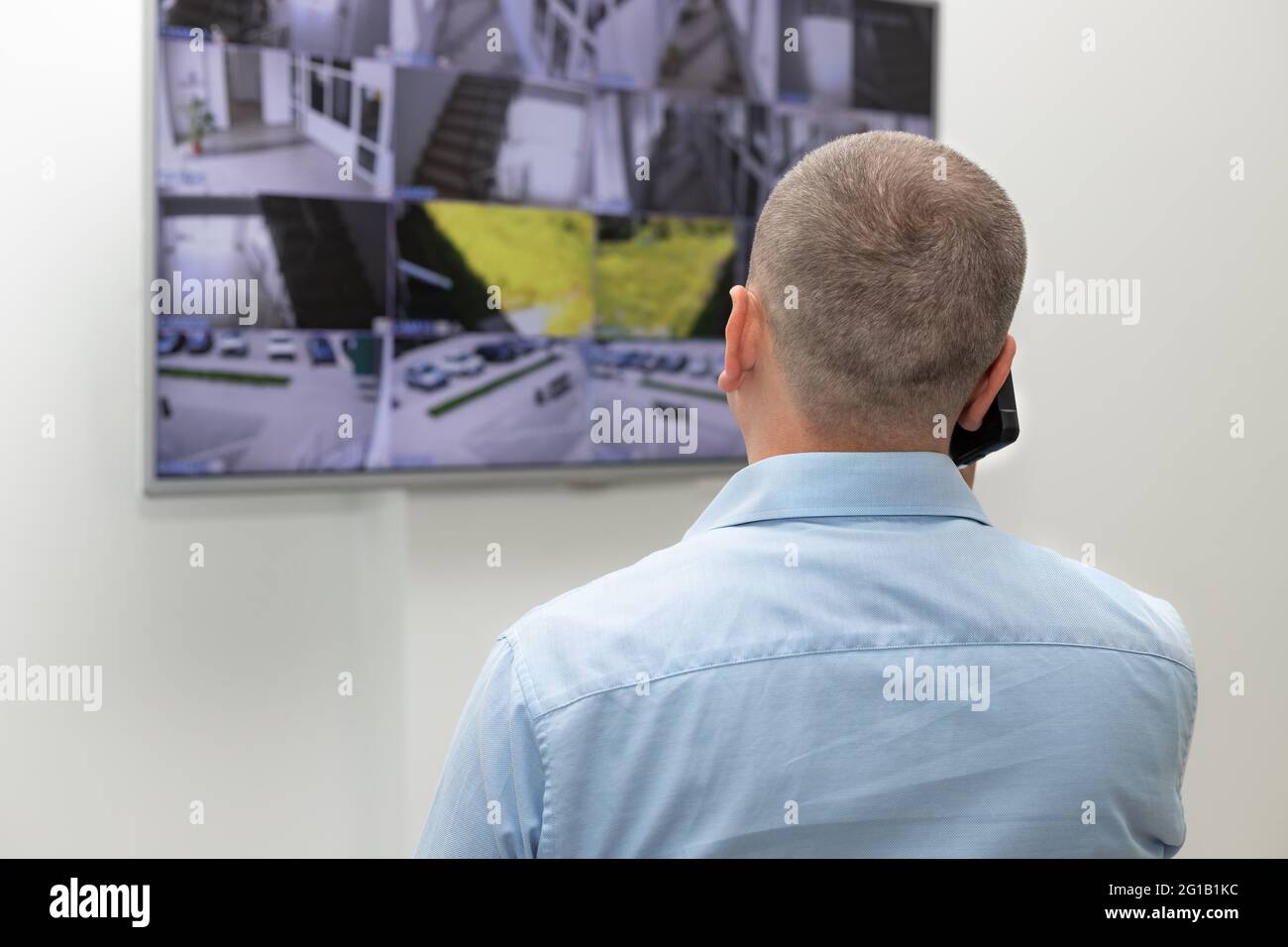 security guard standing in front of large CCTV monitor Stock Photo - Alamy