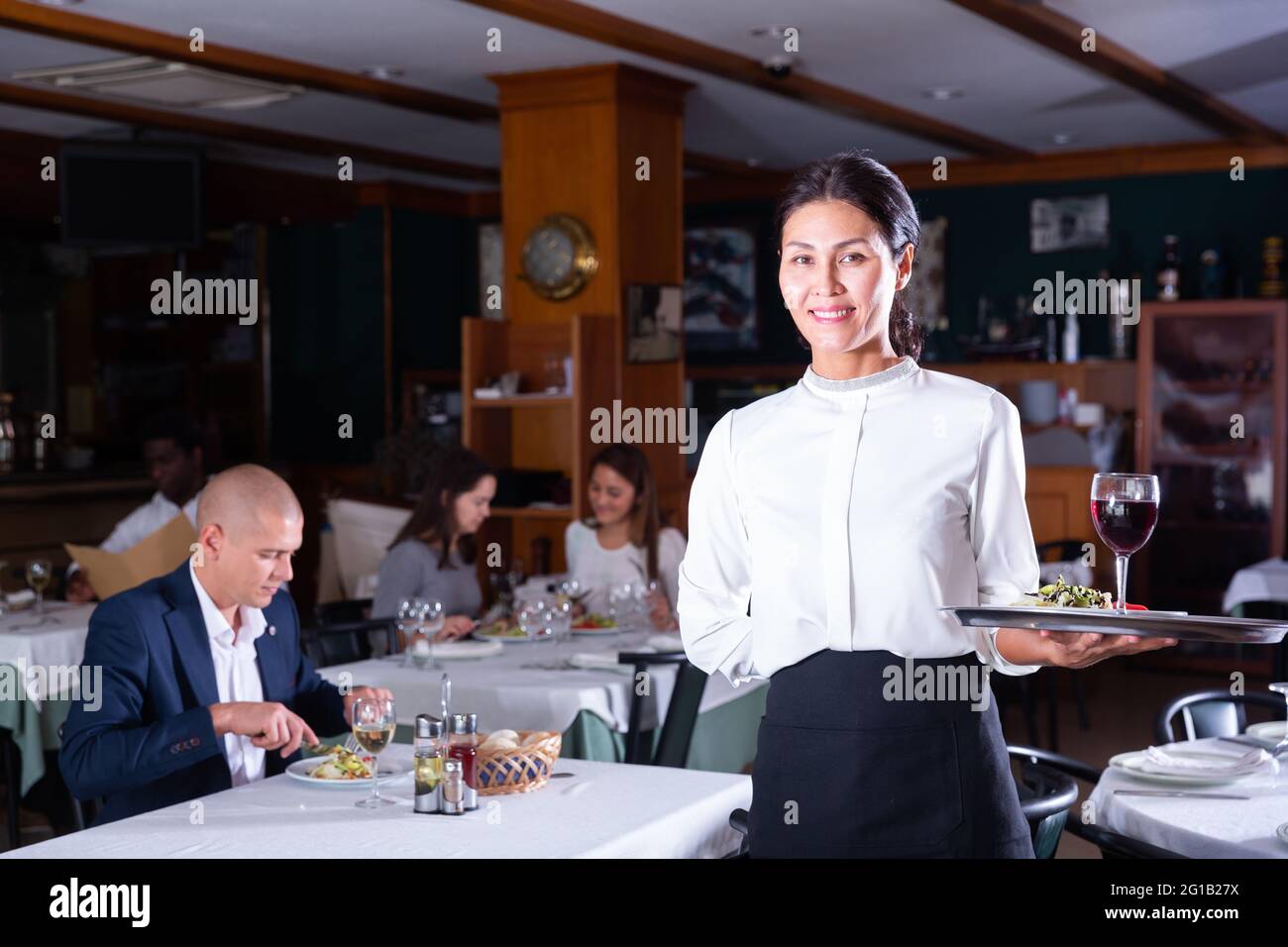 portrait of smiling female waiter standing in modern restaurante Stock ...