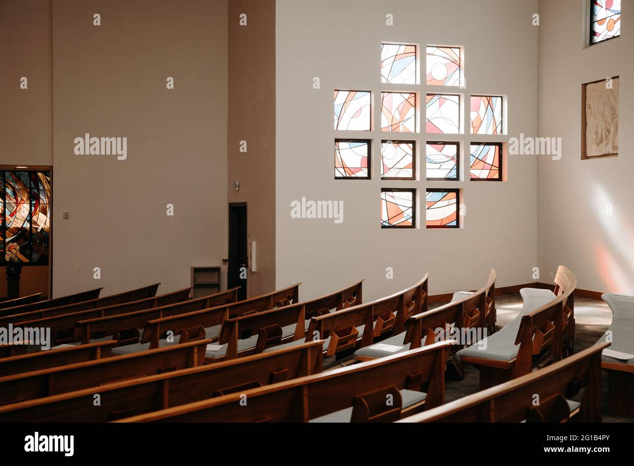 Catholic church - starined glass window with rows of pews and pulpit ...