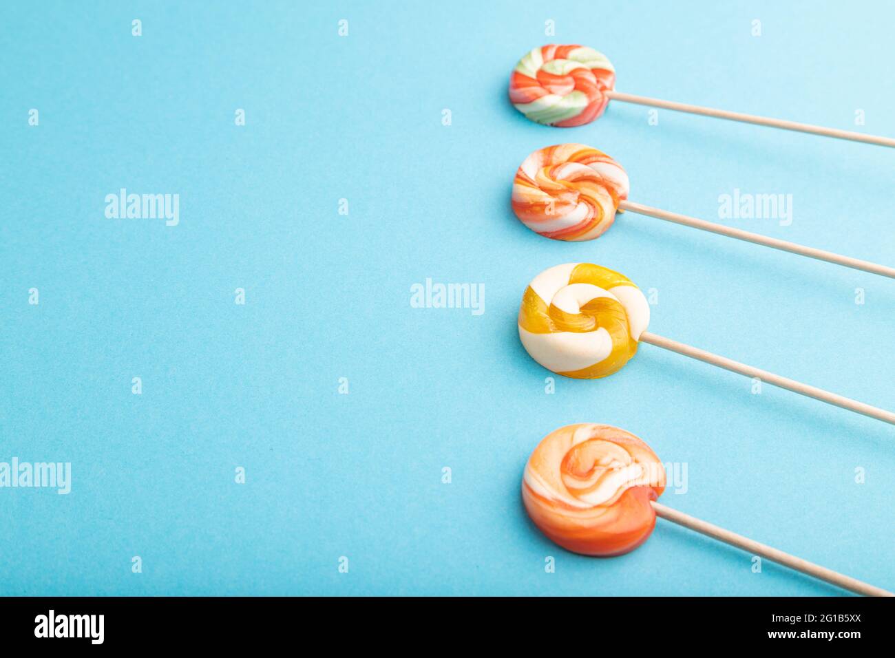 Four lollipop candies on blue pastel background. copy space, side view ...