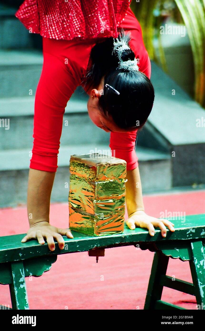 A female acrobat from a troupe of performing acrobats performs at an ...