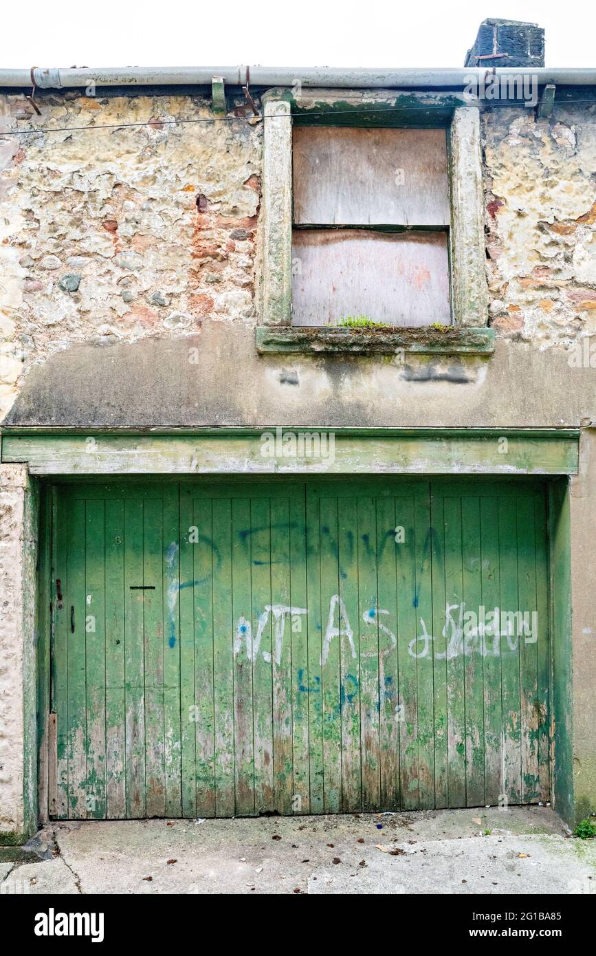 Derelict building with blocked in window and green wooden door Stock ...