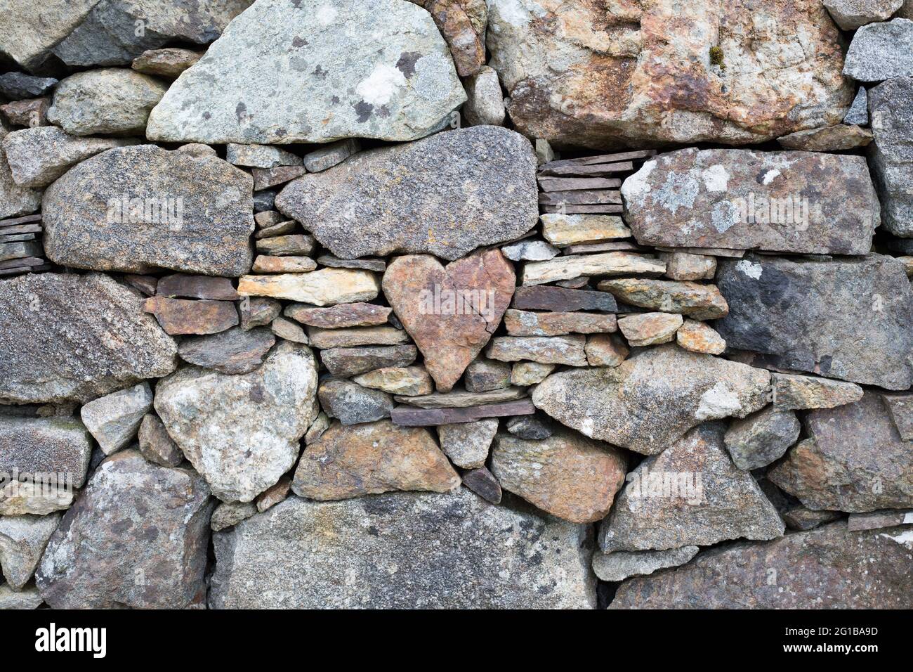 A heart-shaped stone stuck in the middle of a wall with other small and ...
