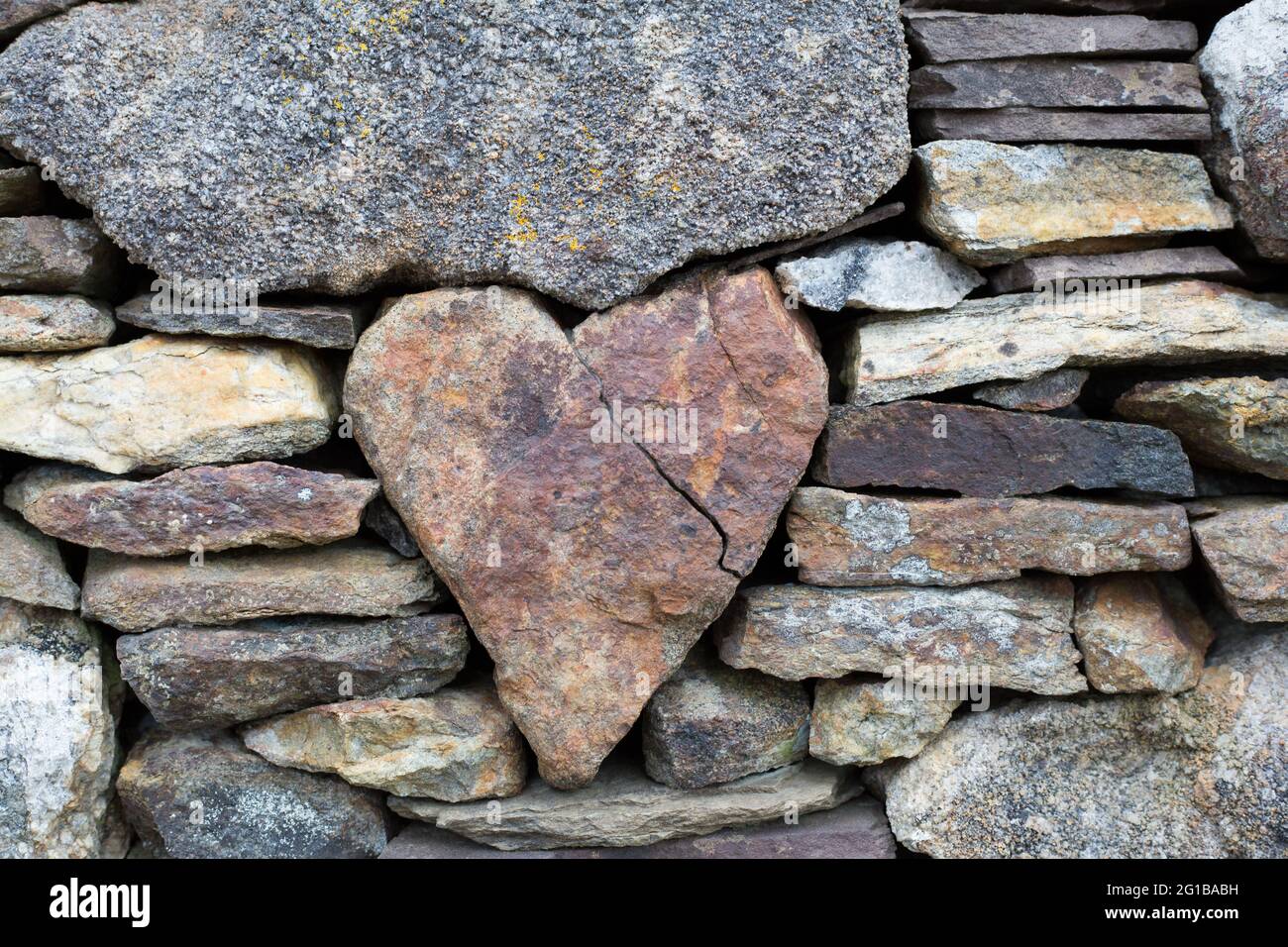 A heart-shaped stone stuck in the middle of a wall with other small and ...