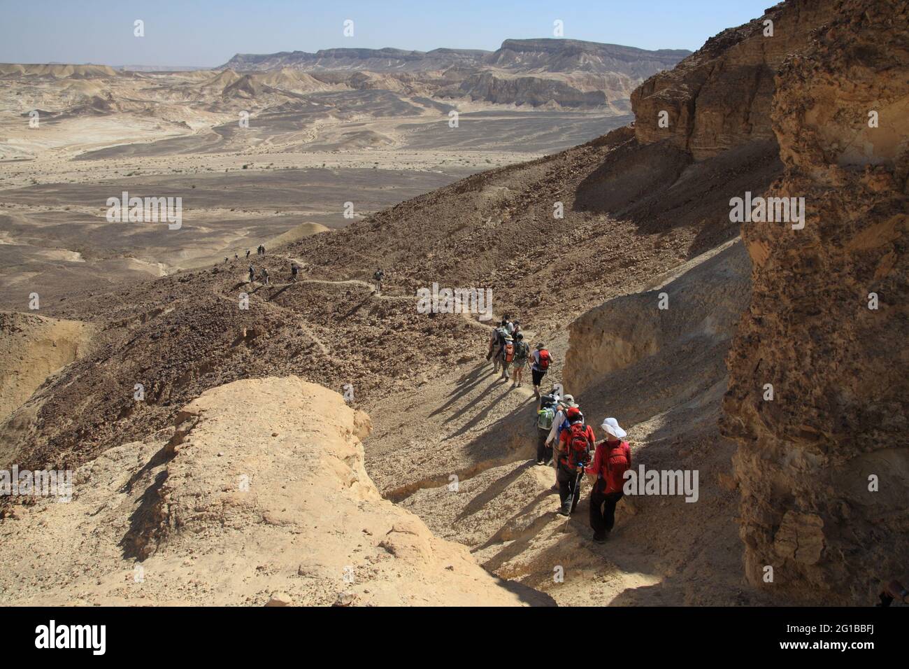 Hikers, senior adults walk on a footpath down to Nachal Sira, dry ...