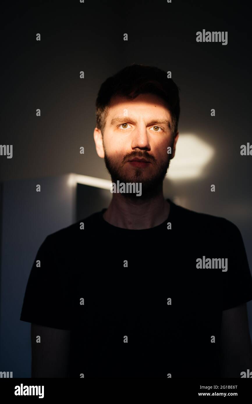 A handsome guy looking at the camera with sun rays falling on his face ...