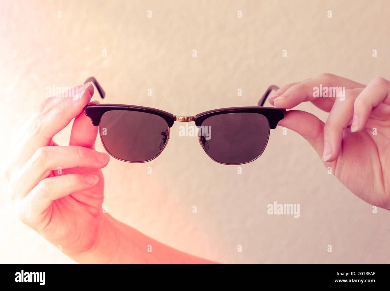 Female hands hold sunglasses on a light background Stock Photo - Alamy