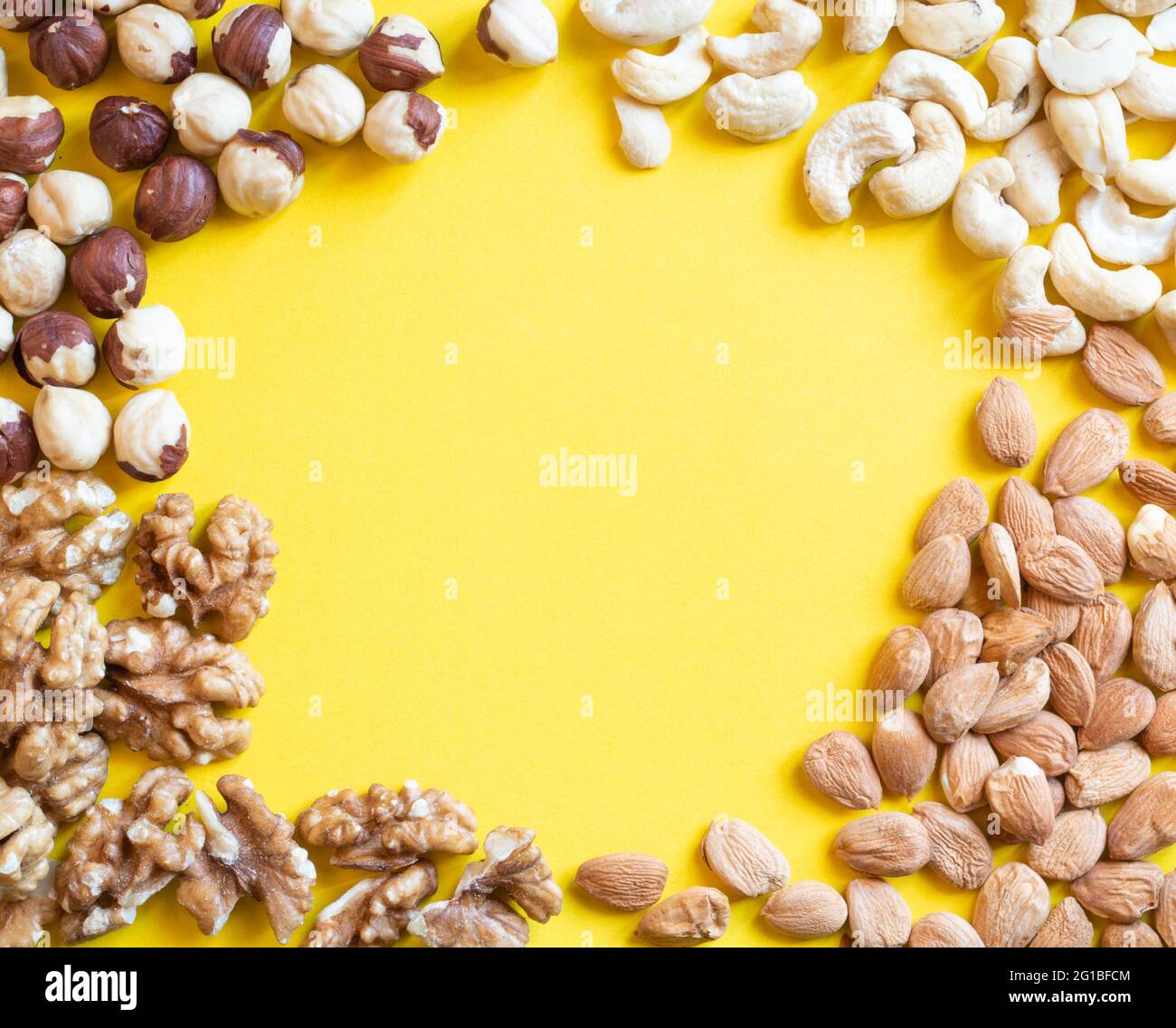 Different delicious nuts on yellow background, flat lay. Space for text ...