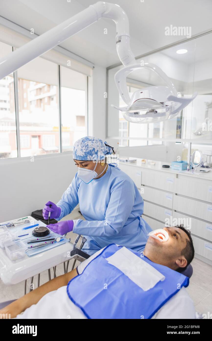 Female stomatologist in uniform and respiratory mask curing teeth of ...