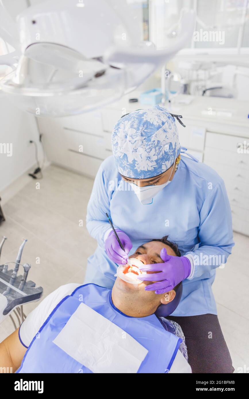 From above of anonymous female doctor in uniform cleaning teeth of male ...