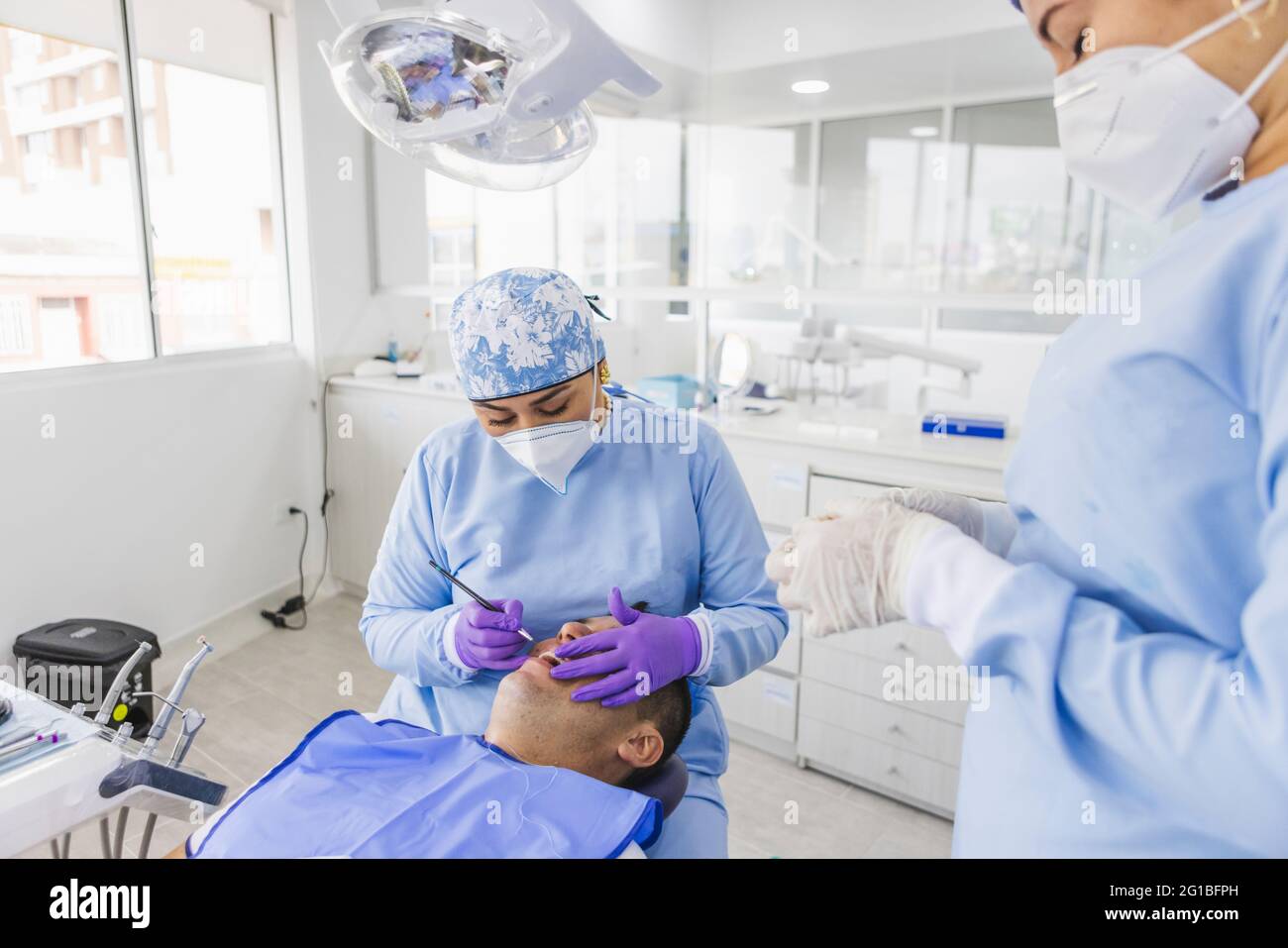 Female stomatologist in uniform and respiratory mask curing teeth of ...