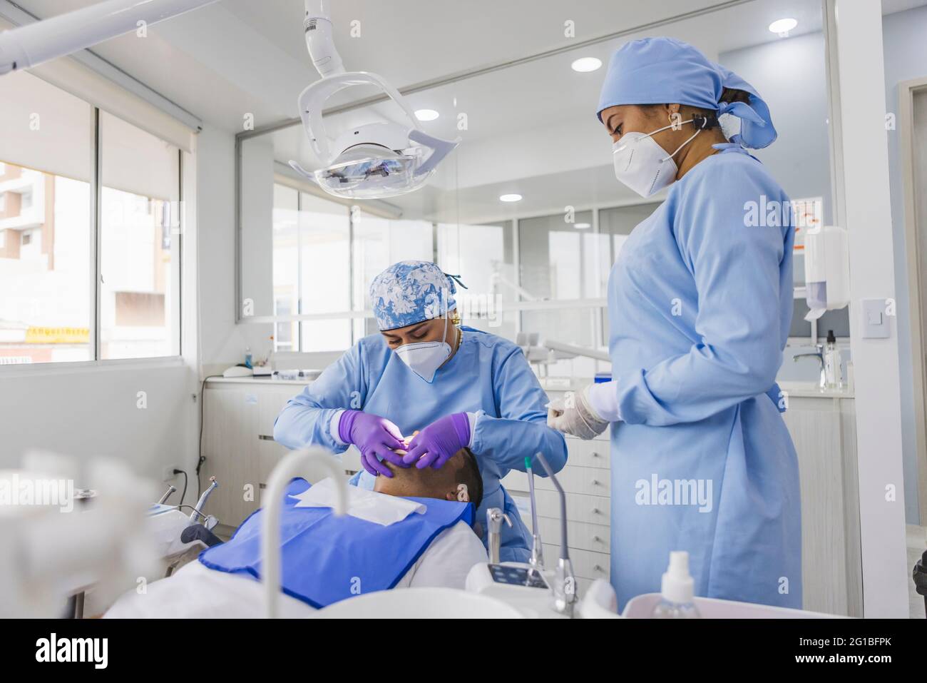 Female stomatologist in uniform and respiratory mask curing teeth of ...