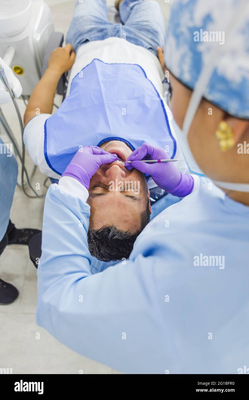 Female stomatologist in uniform and respiratory mask curing teeth of ...