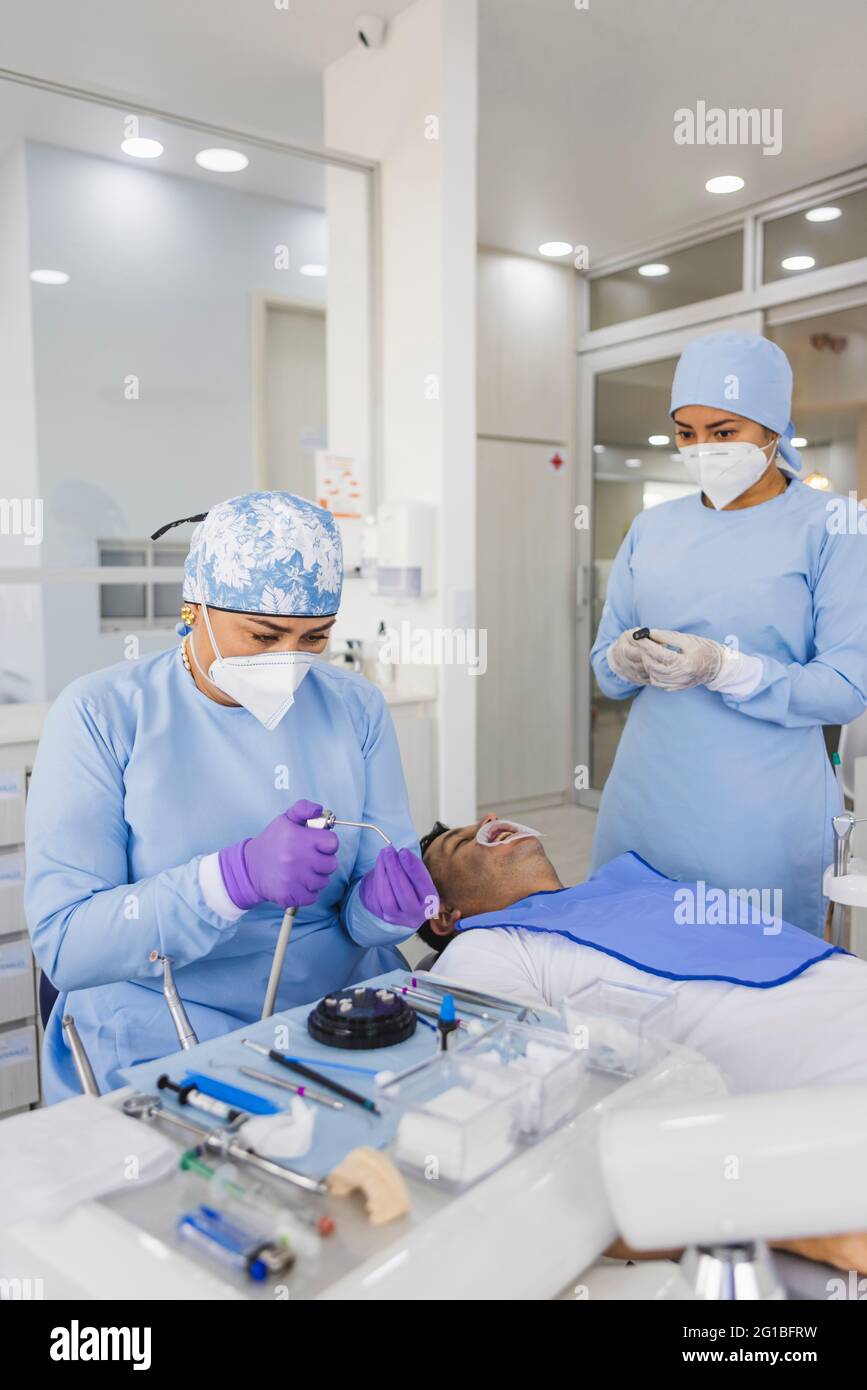 Female dentist with tool preparing veneers for procedure in clinic ...