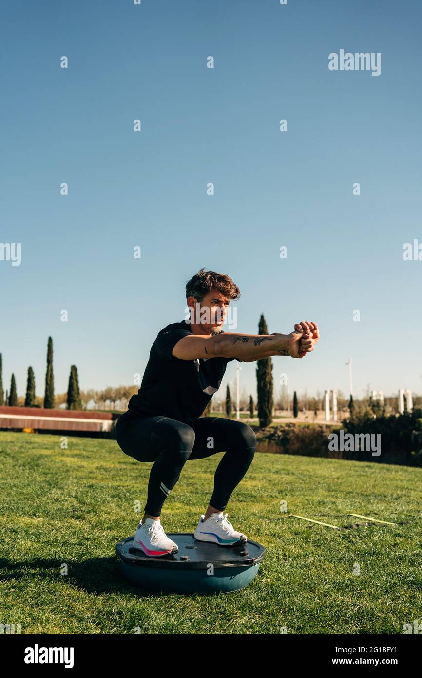Determined male athlete with tattoos and outstretched arms training on ...