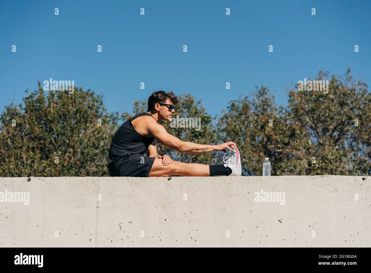 Side view of muscular male athlete in activewear leaning forward during ...
