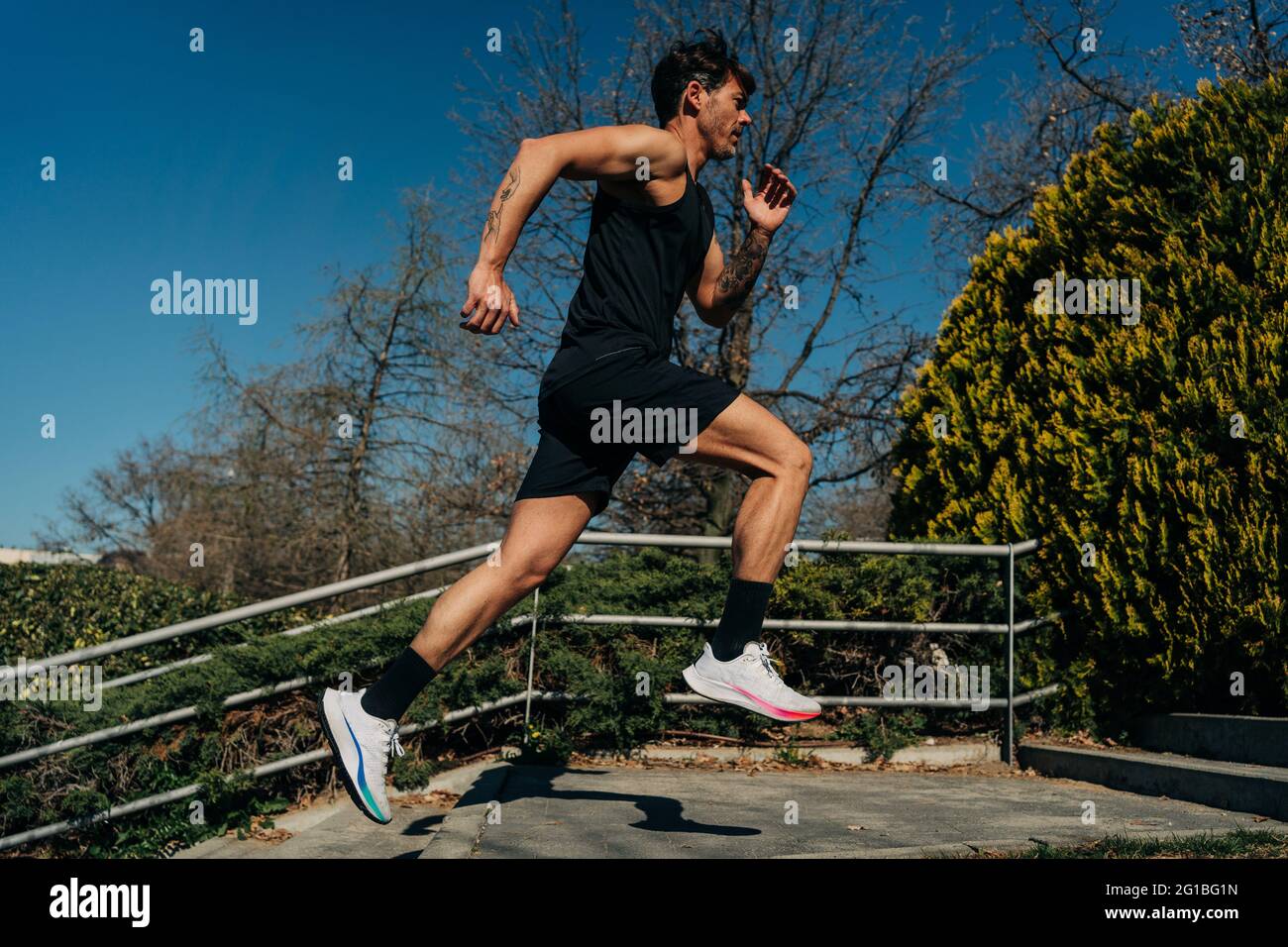 Side view of active male jogger in sportswear running on staircase ...