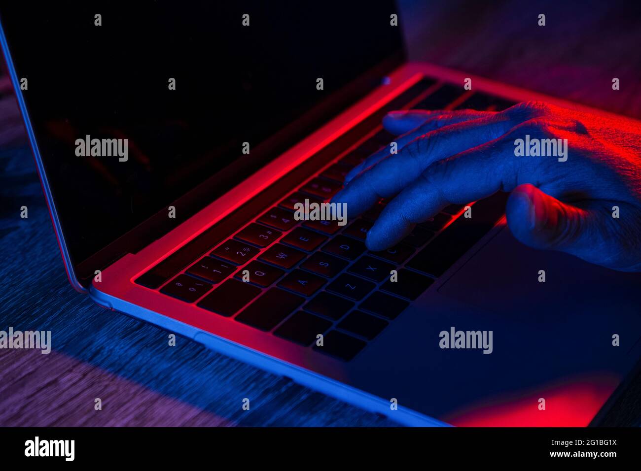 Crop anonymous male using laptop with black screen placed on wooden ...