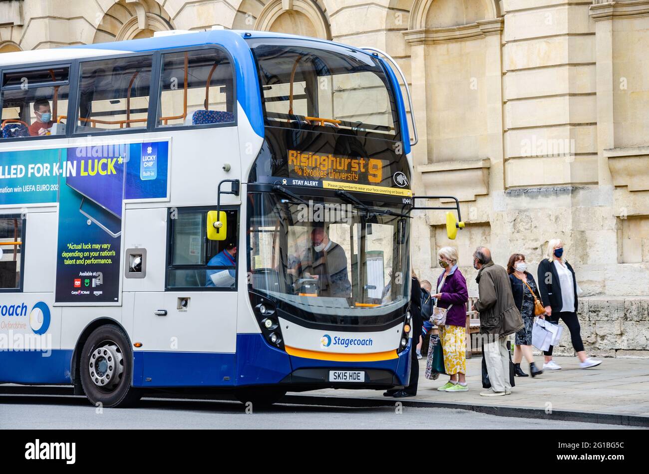 A bus stops outside University of Oxford, Queen's College on the High ...