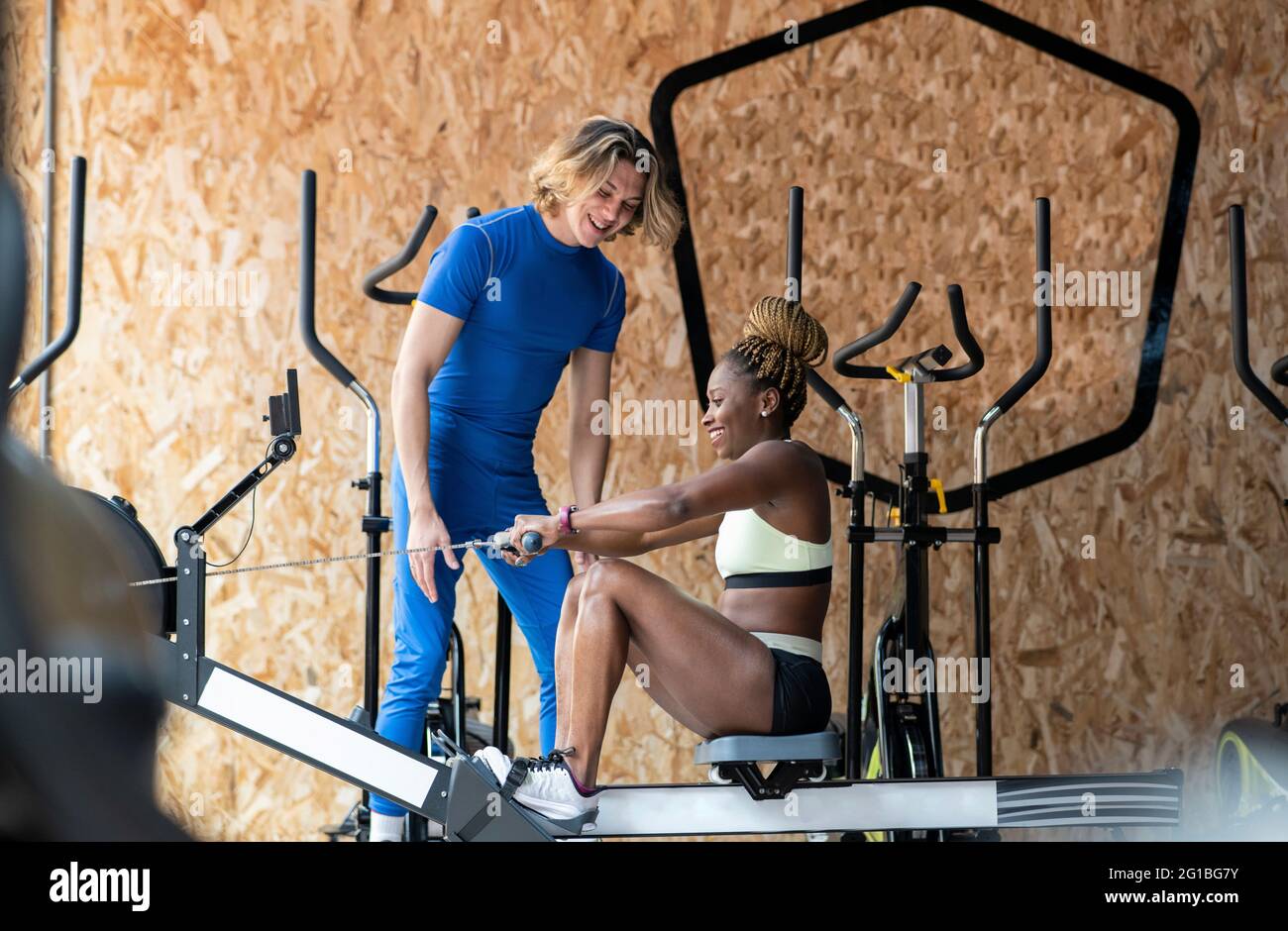 Smiling male athlete helping ethnic female partner working out on ...