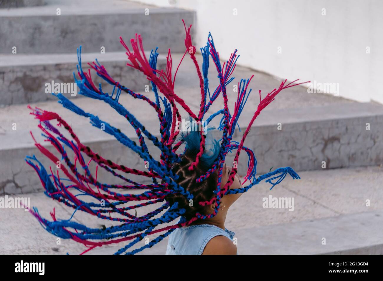 Side view of ethnic child with flying colorful braids standing near ...