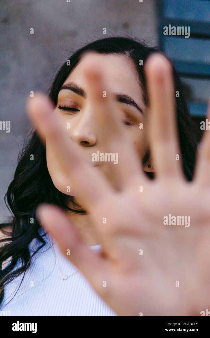 Female teenager with closed eyes and wavy hair demonstrating defense ...