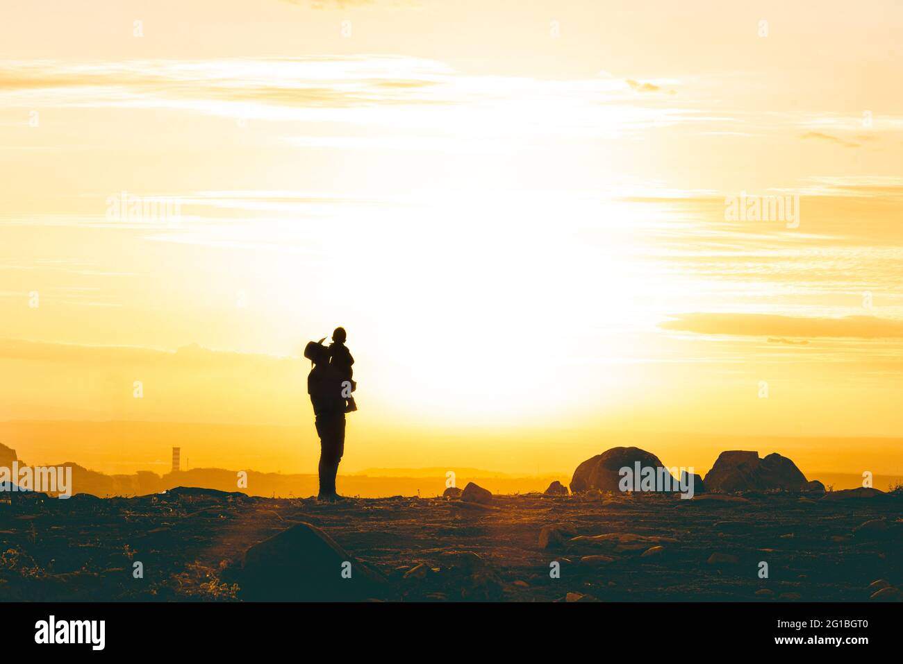 Side view of anonymous male holding child in air in rocky rough valley ...