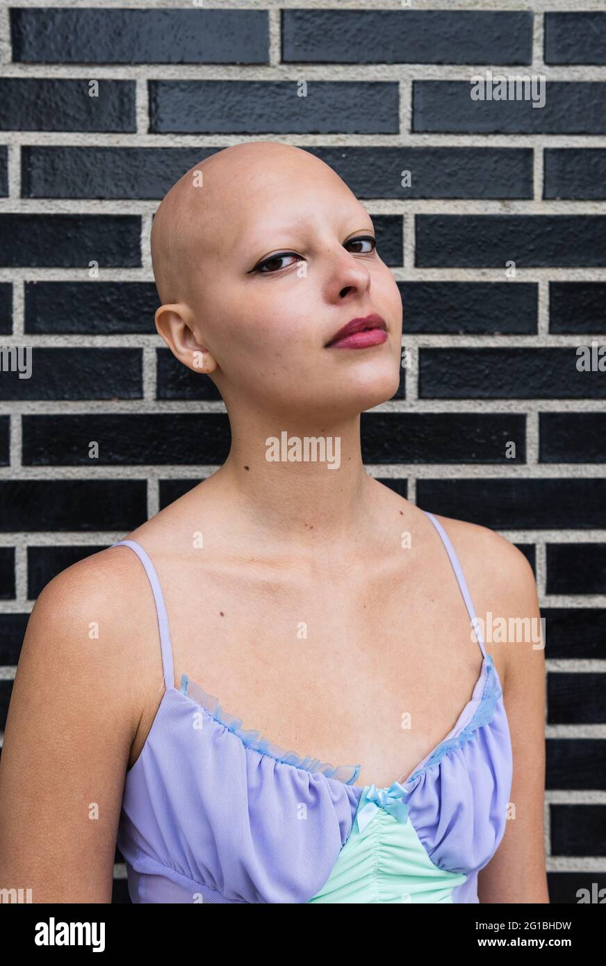 Confident young bald lady in colorful shirt and makeup standing near ...