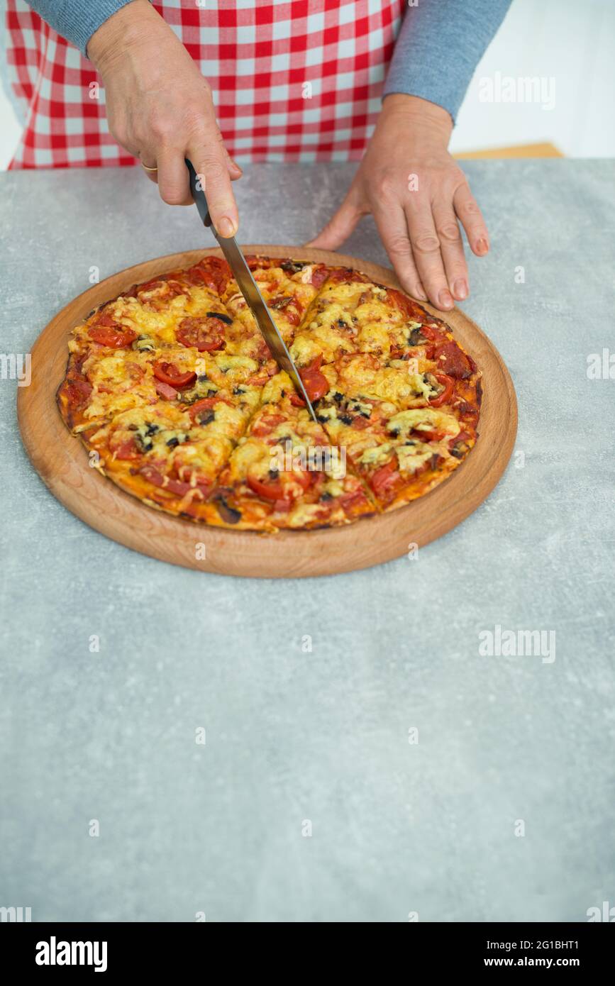 Someone is cutting the finished pizza into sections of the sector for ...