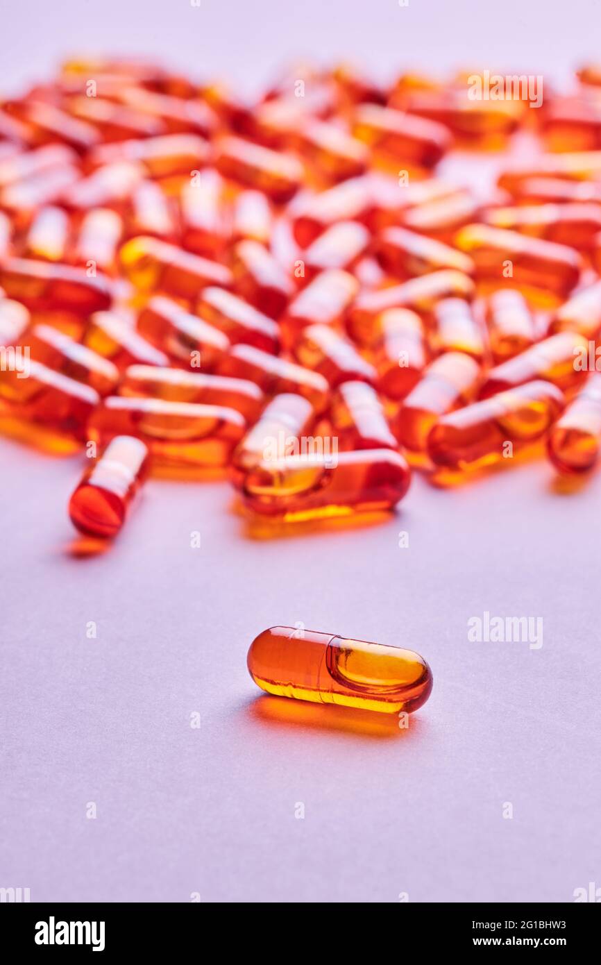 Composition of orange pills scattered on pink background in light ...