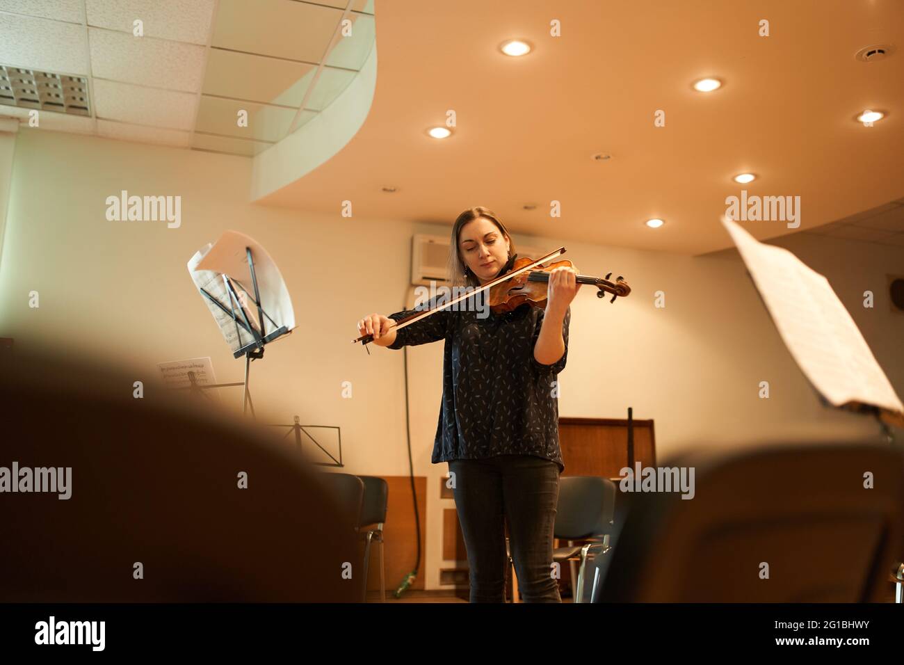 Focused professional female musician playing acoustic violin with eyes ...