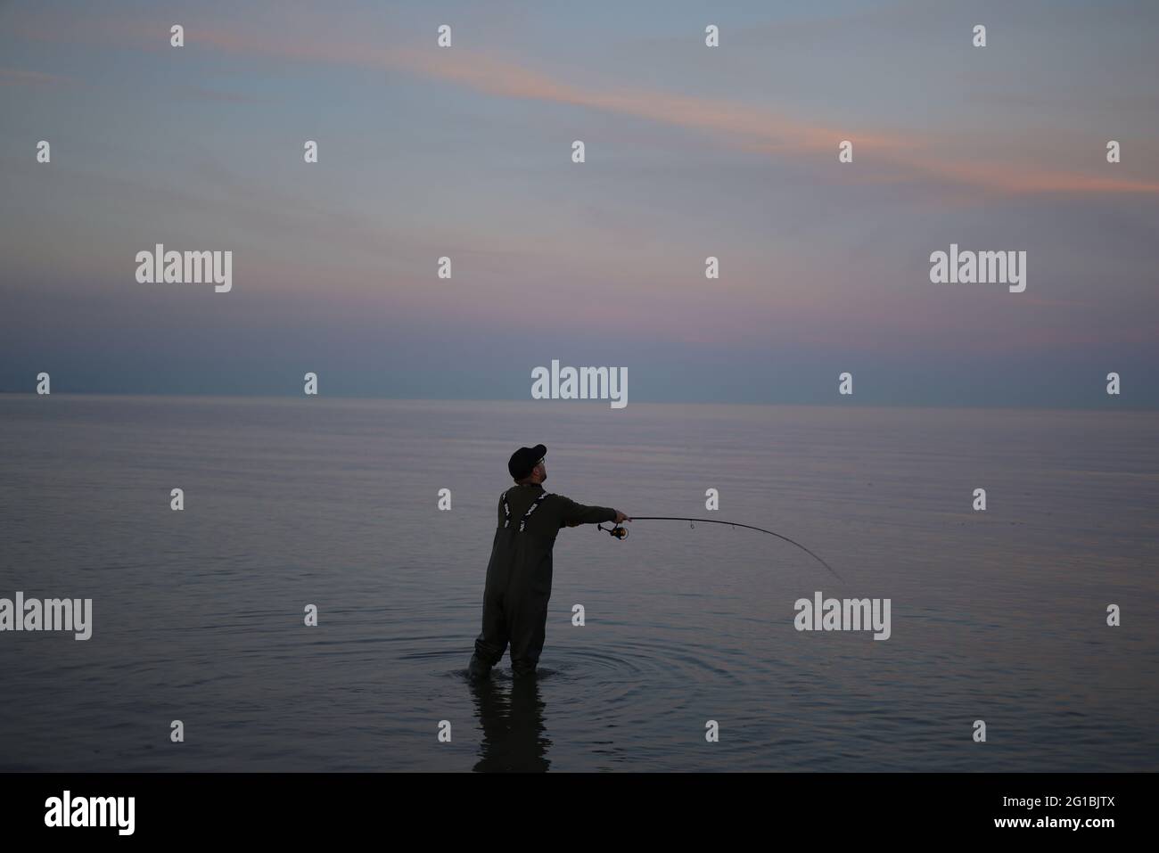 Angler seen fishing on the beach Stock Photo - Alamy