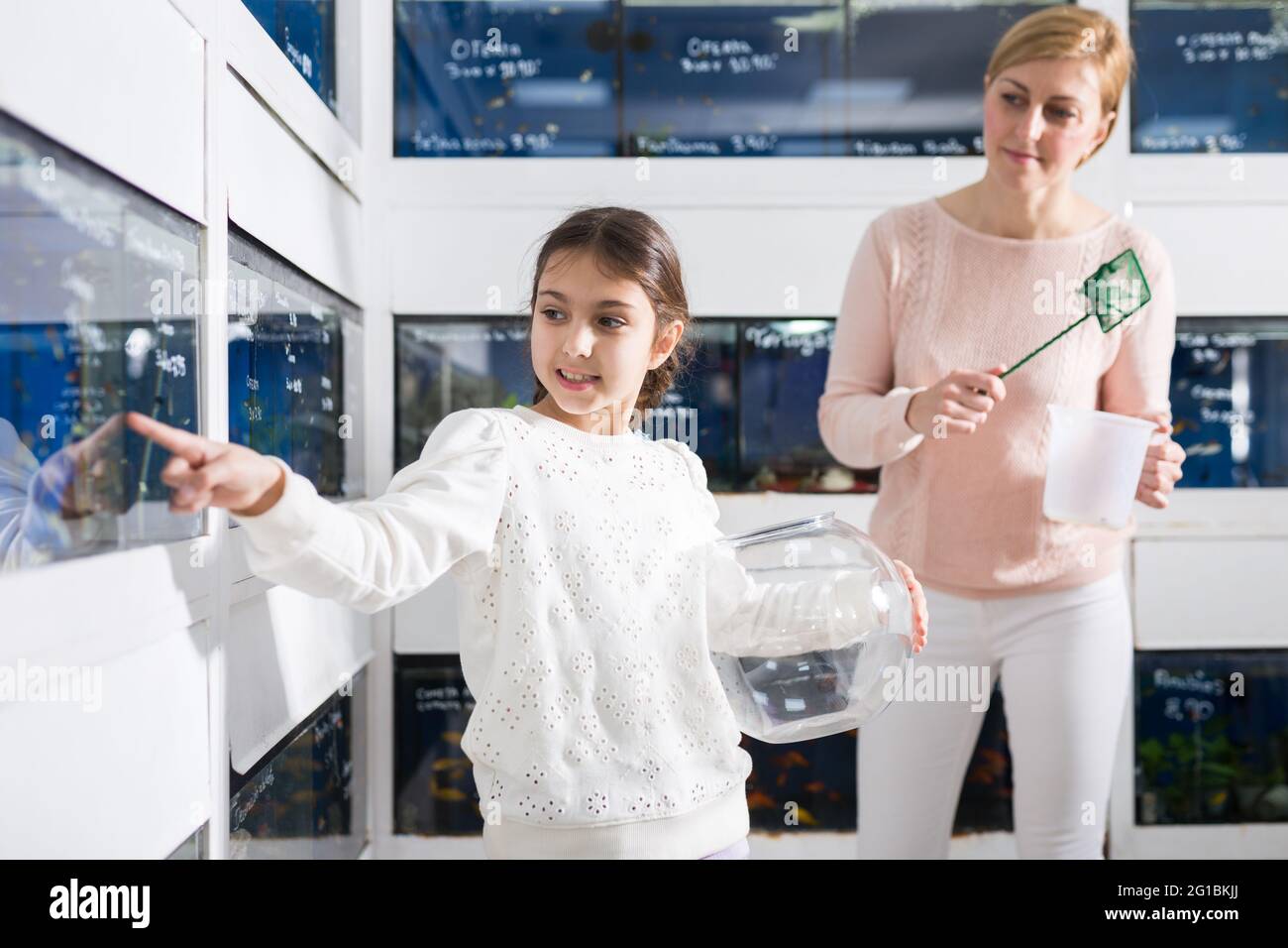 Girl with mother choosing aquarium fish Stock Photo - Alamy