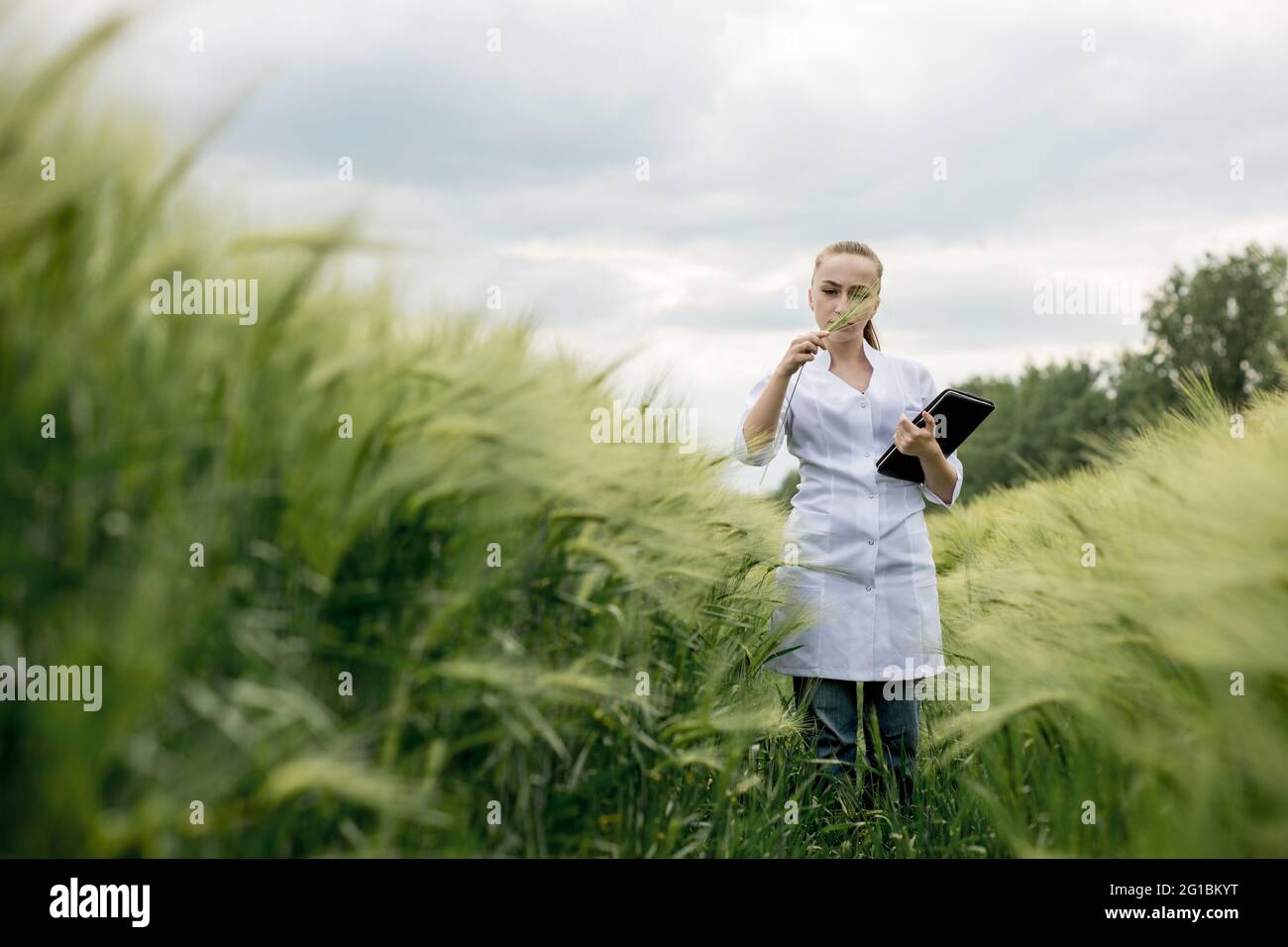 Young female ecologist scientist in goggles standing in green field and ...