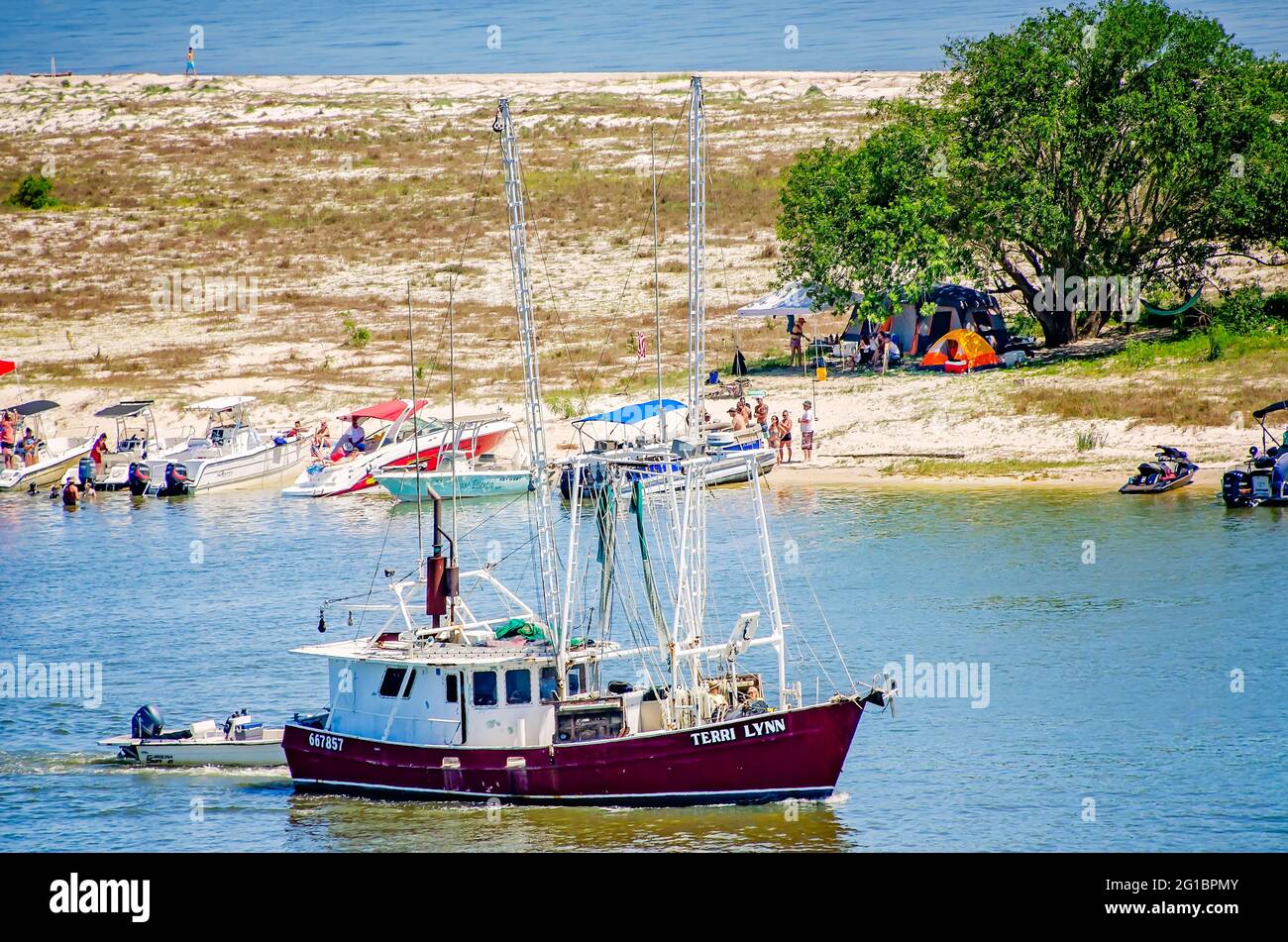 A shrimp boat passes boaters enjoying Deer Island on Memorial Day ...
