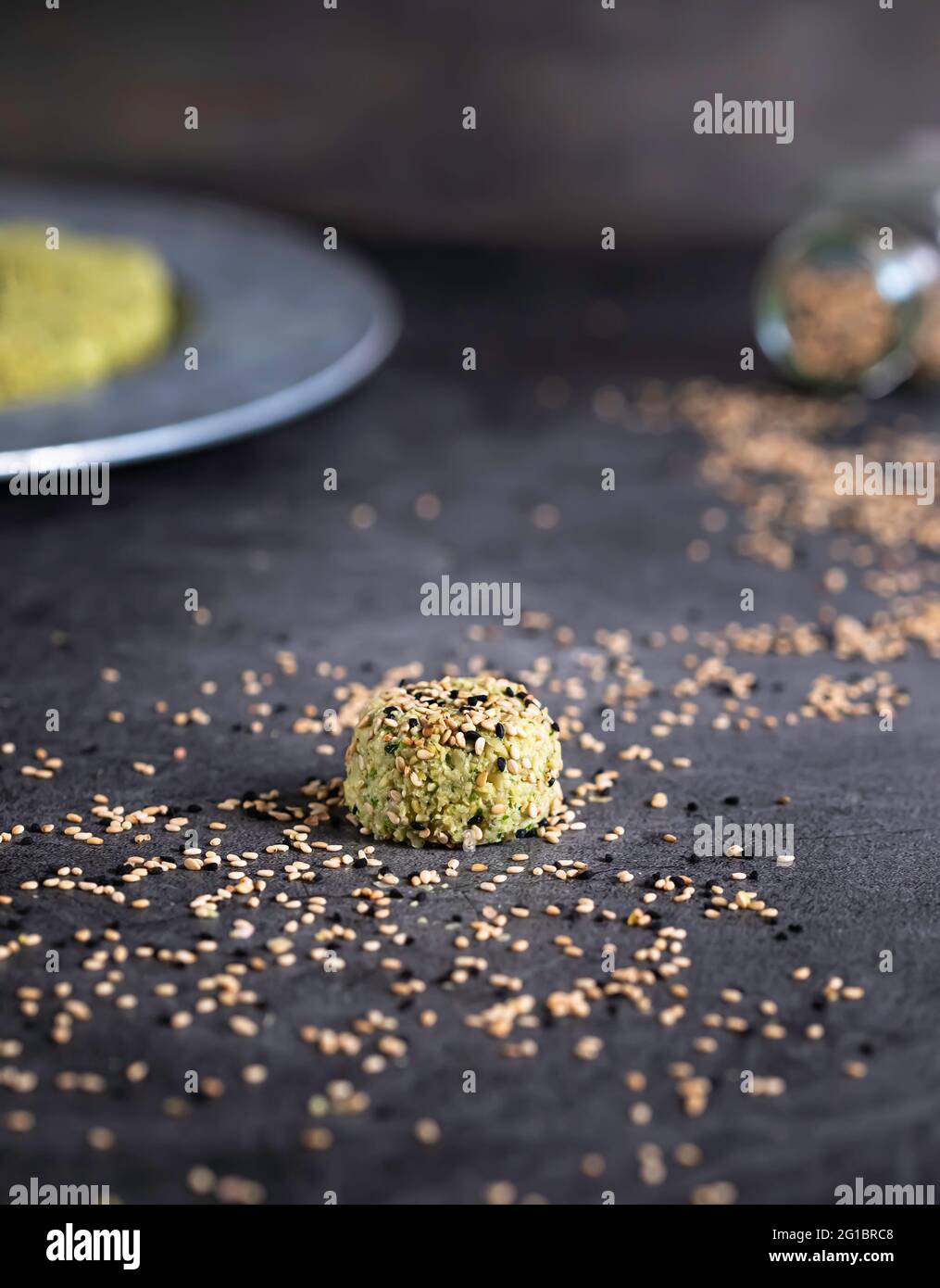 Single falafel in close up drizzled with sesame seeds. Grey background ...